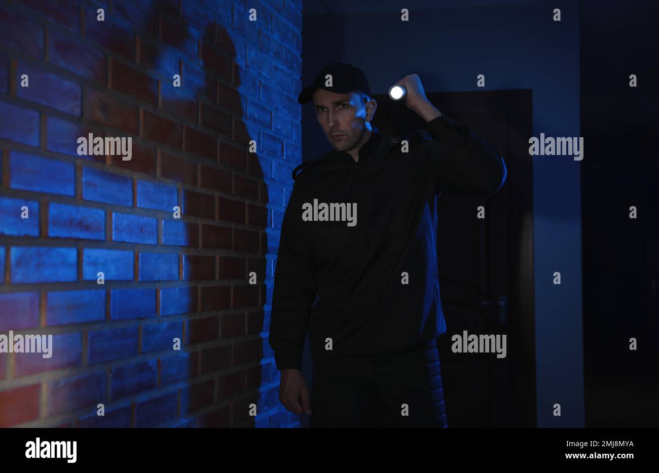 Male security guard with flashlight in dark corridor Stock Photo - Alamy
