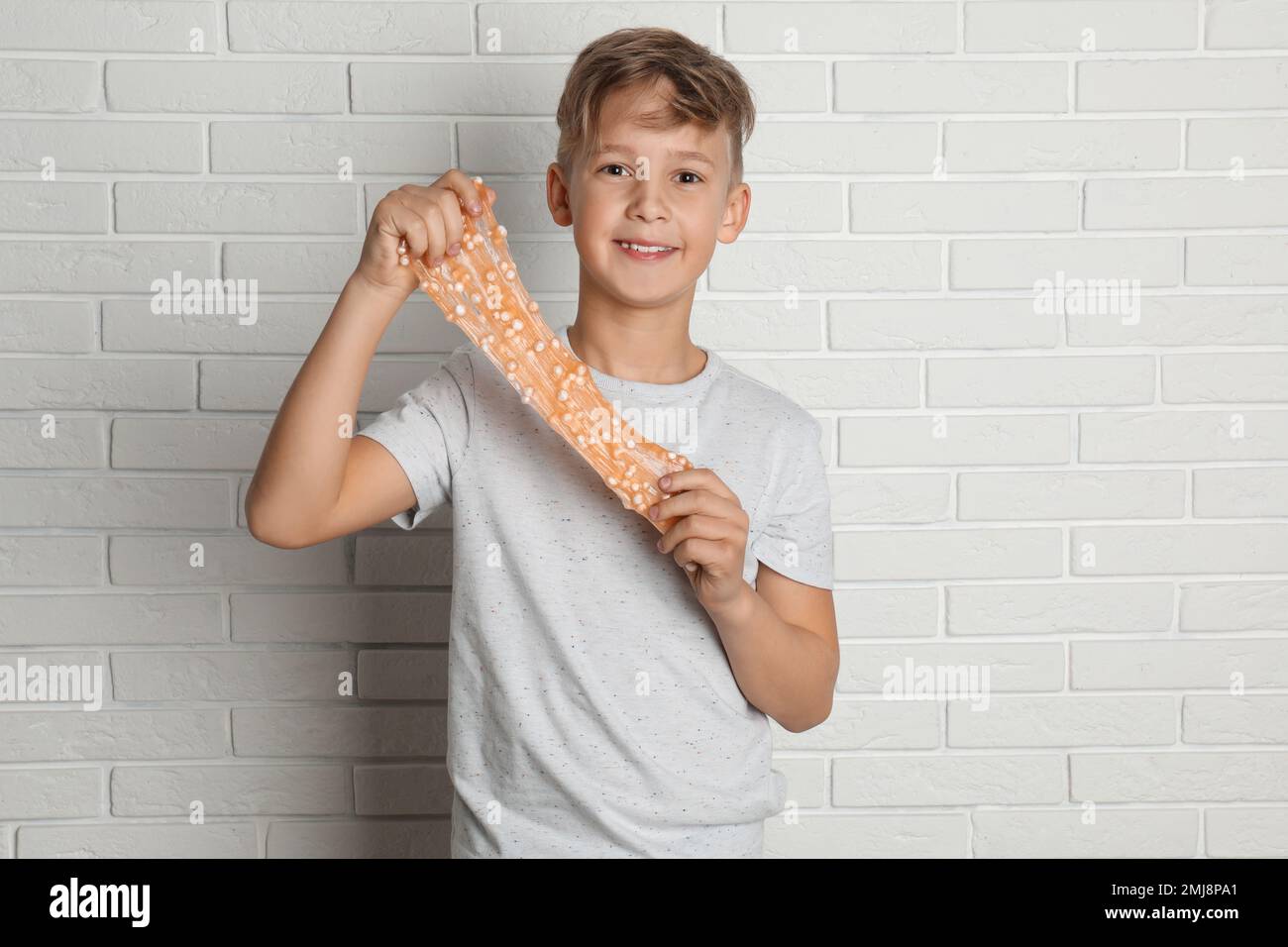 Preteen boy with slime near white brick wall Stock Photo - Alamy