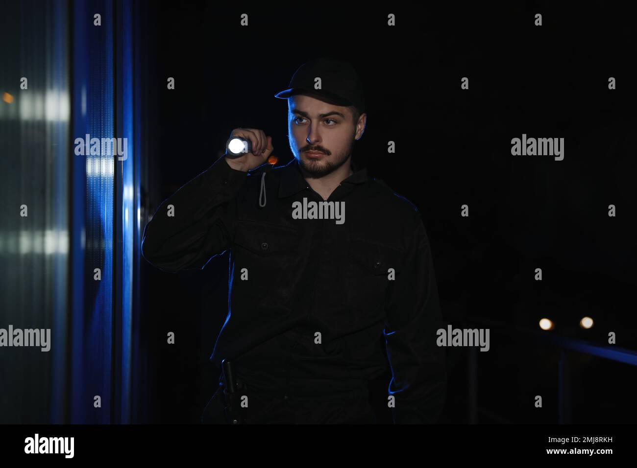 Male security guard with flashlight in dark corridor Stock Photo - Alamy