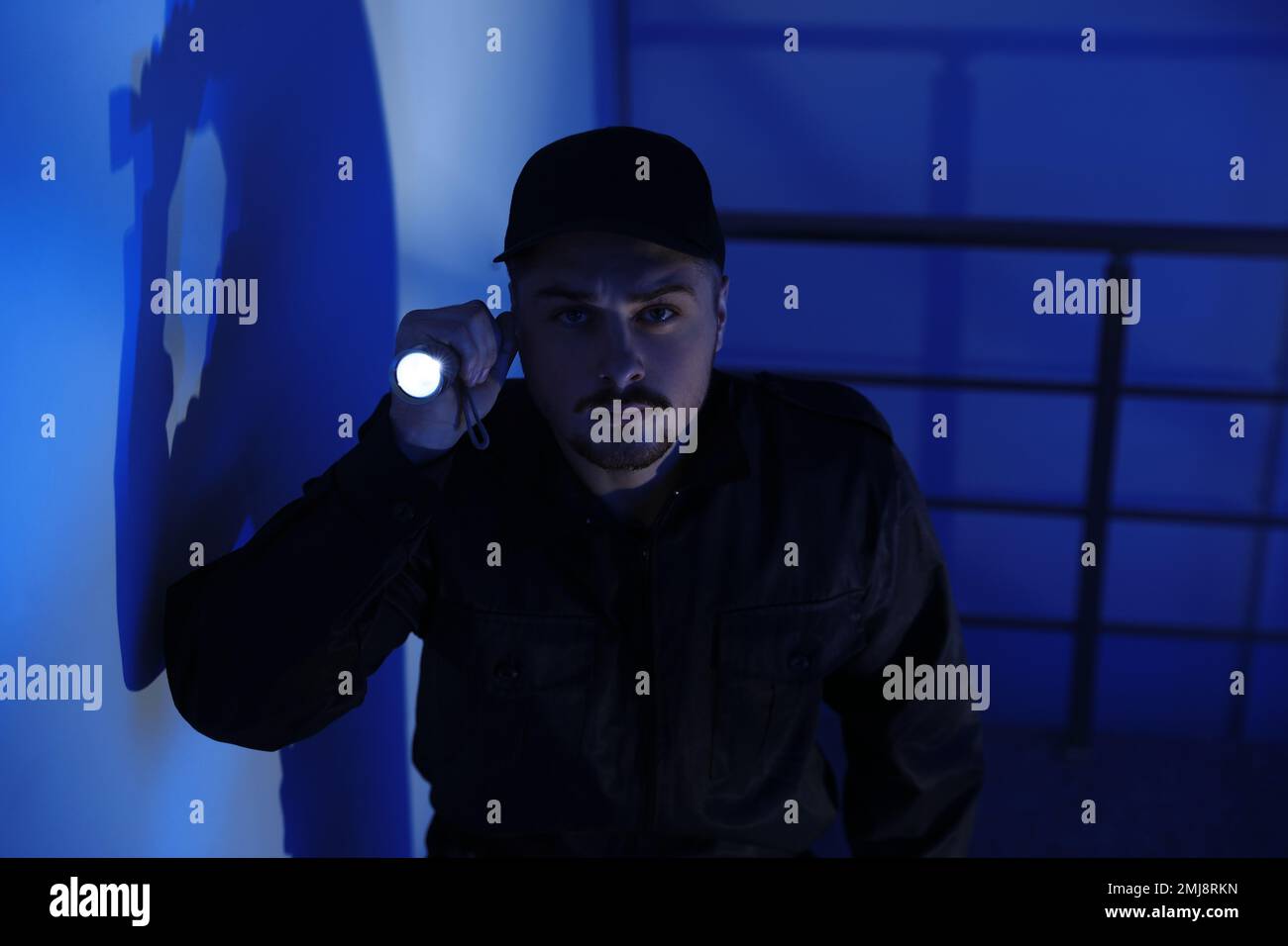 Male security guard with flashlight in dark room Stock Photo - Alamy