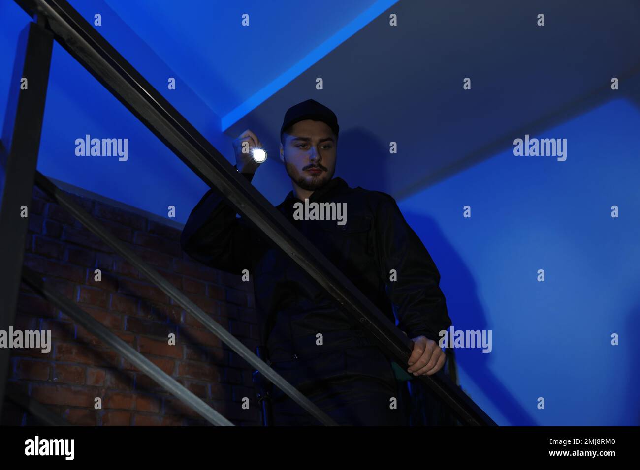 Male security guard with flashlight on stairs in darkness Stock Photo ...