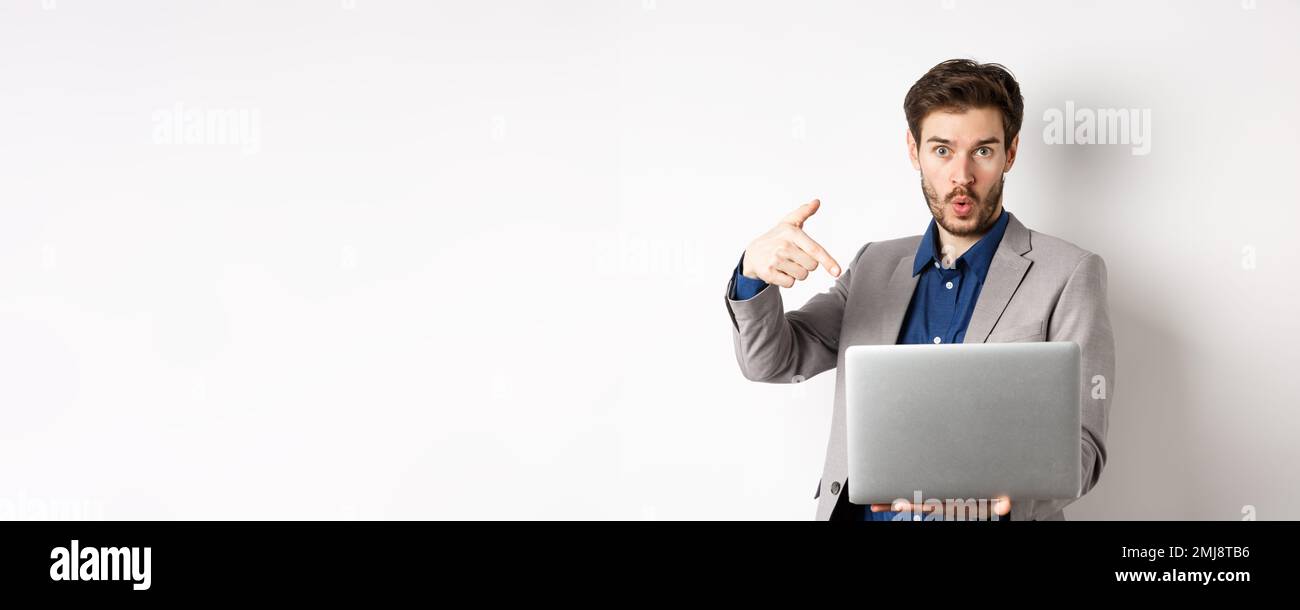 Excited handsome man asking to look here, pointing at laptop screen ...
