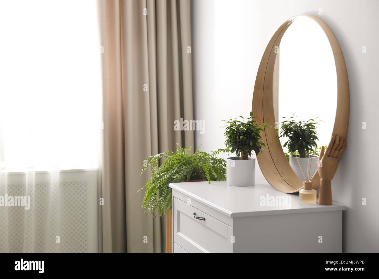 Round mirror and chest of drawers near white wall in room. Modern ...