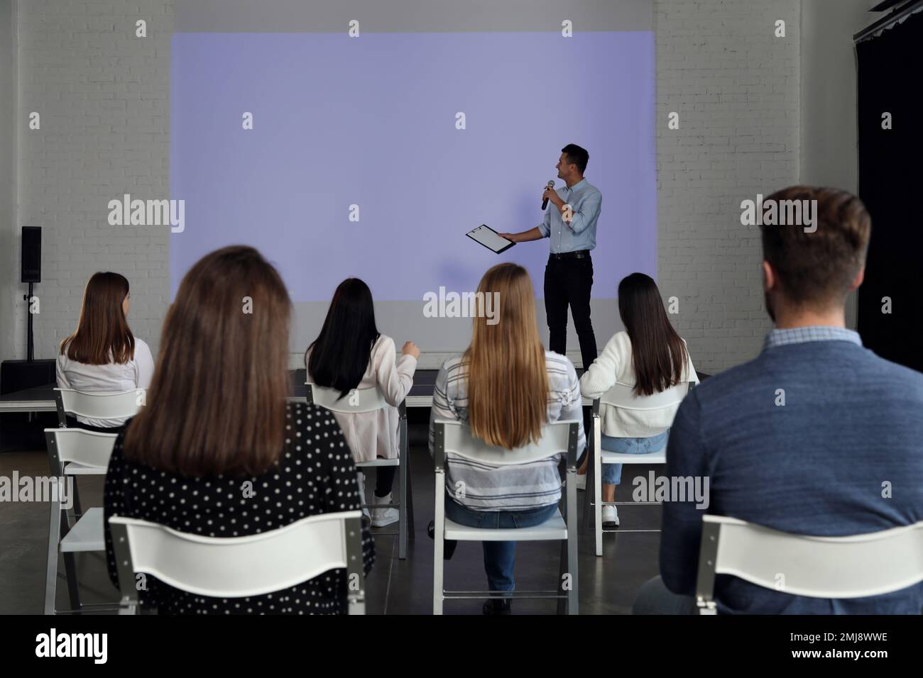 Male business trainer giving lecture in conference room with projection ...
