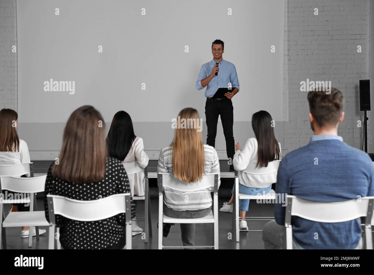 Male business trainer giving lecture in conference room with projection ...