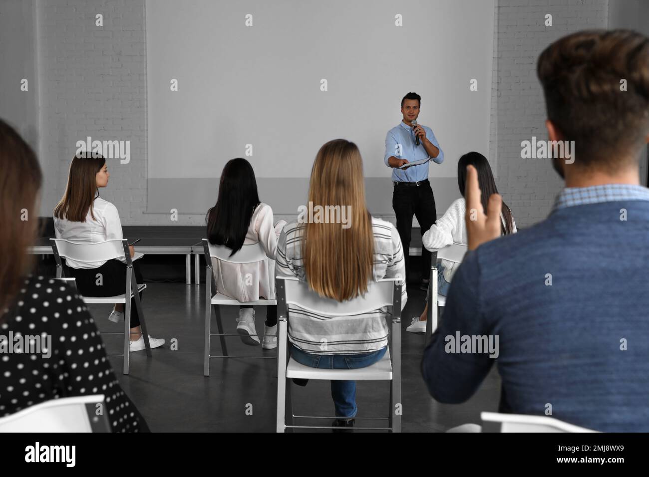 Male business trainer giving lecture in conference room with projection ...