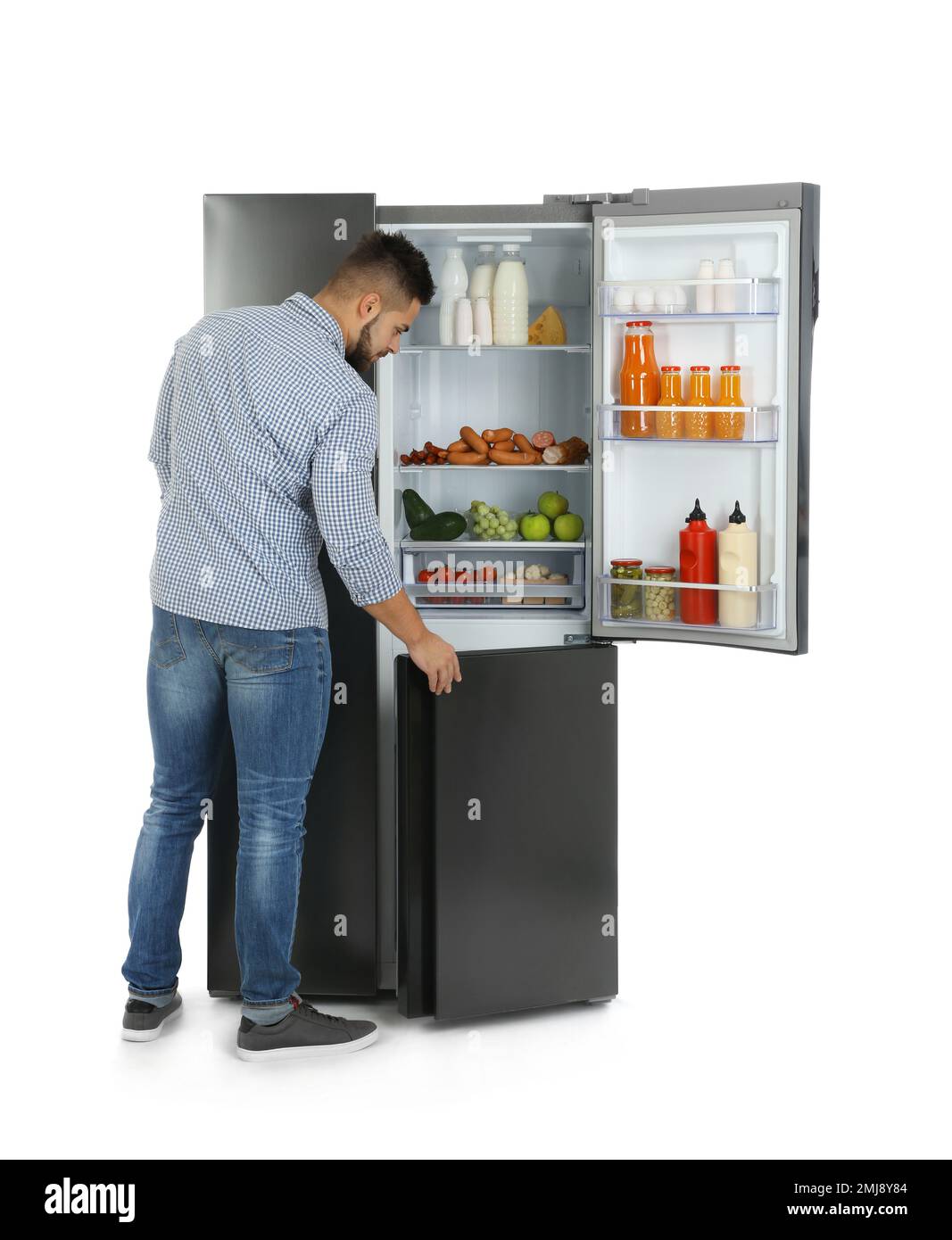Young man opening refrigerator on white background Stock Photo - Alamy