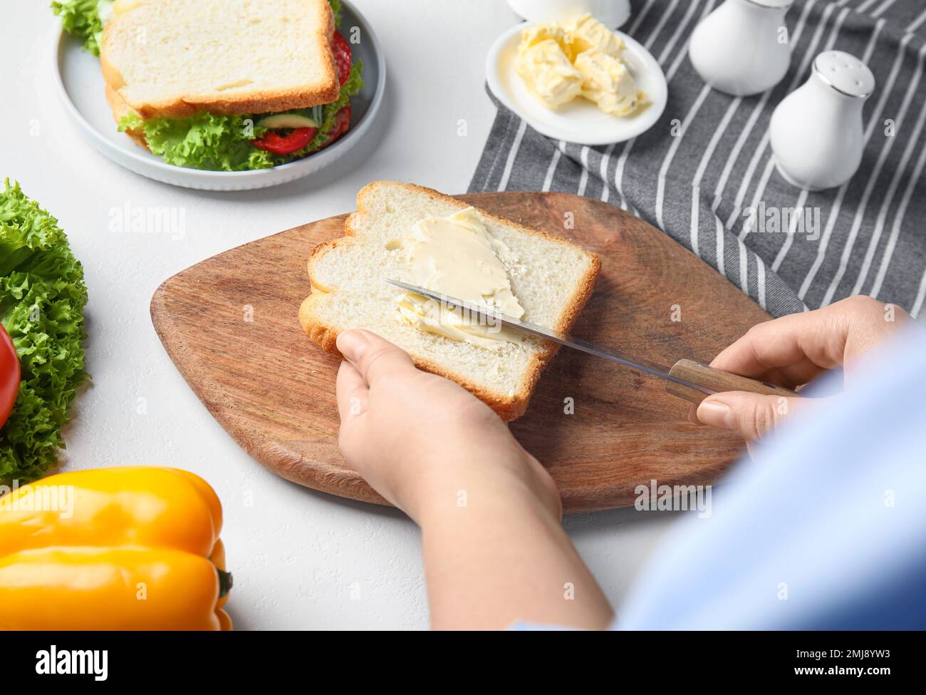 Woman spreading butter on sandwich at white table, closeup Stock Photo ...