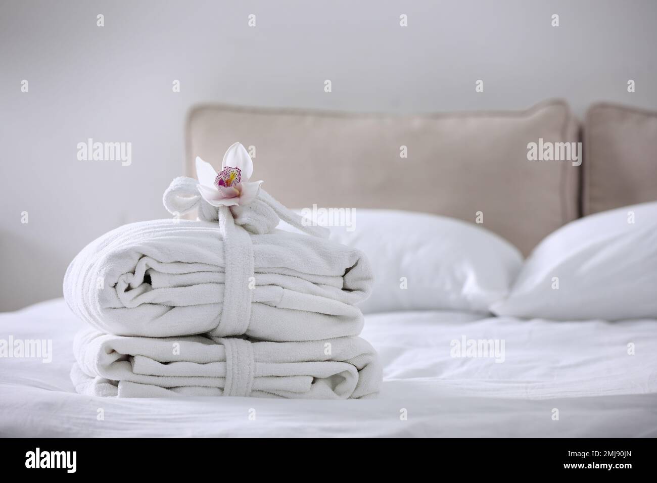 Clean folded bathrobes on bed in room, space for text Stock Photo - Alamy
