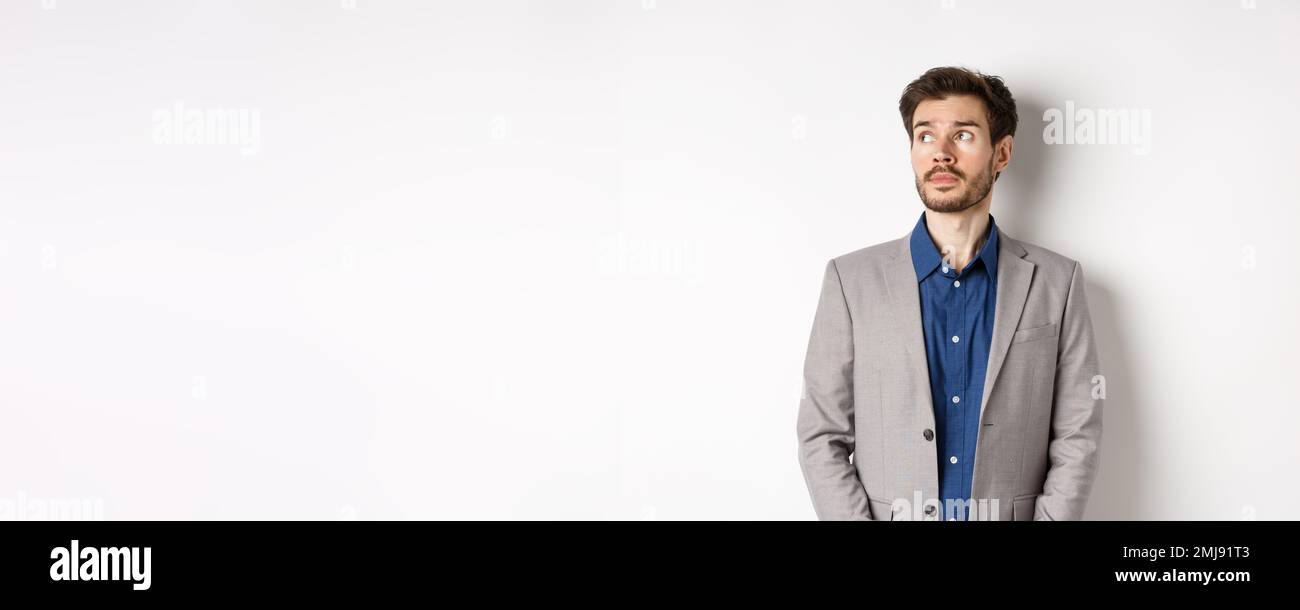 Thoughtful sad businessman in suit looking at upper left corner logo ...