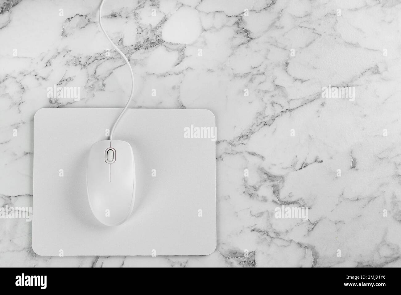 Modern wired optical mouse and pad on white marble table, top view ...