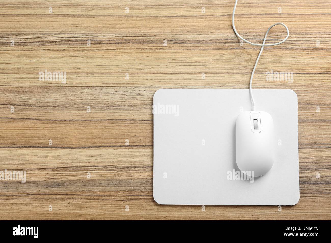 Modern wired optical mouse and pad on wooden table, top view. Space for ...
