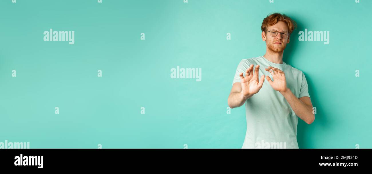 Reluctant redhead man in glasses raising hands in refusal gesture, step ...