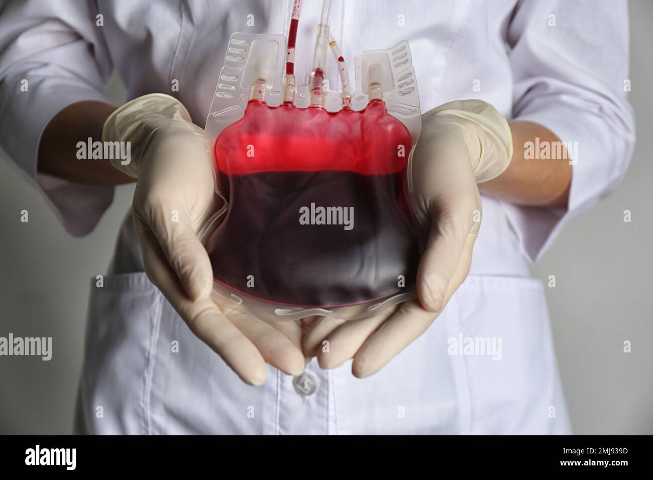 Woman holding blood for transfusion on light grey background, closeup ...