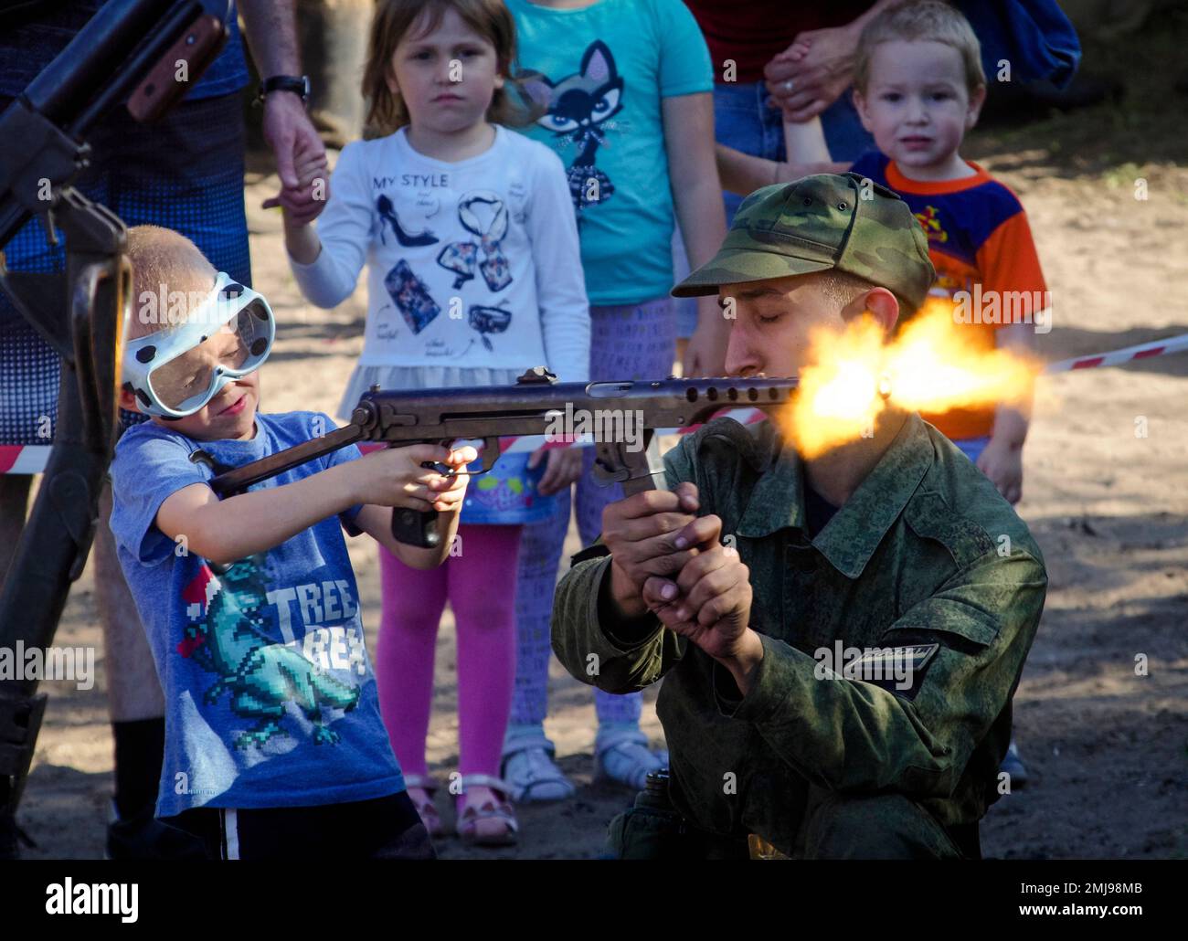 A military instructor helps a boy shoot a World War II blank machine ...