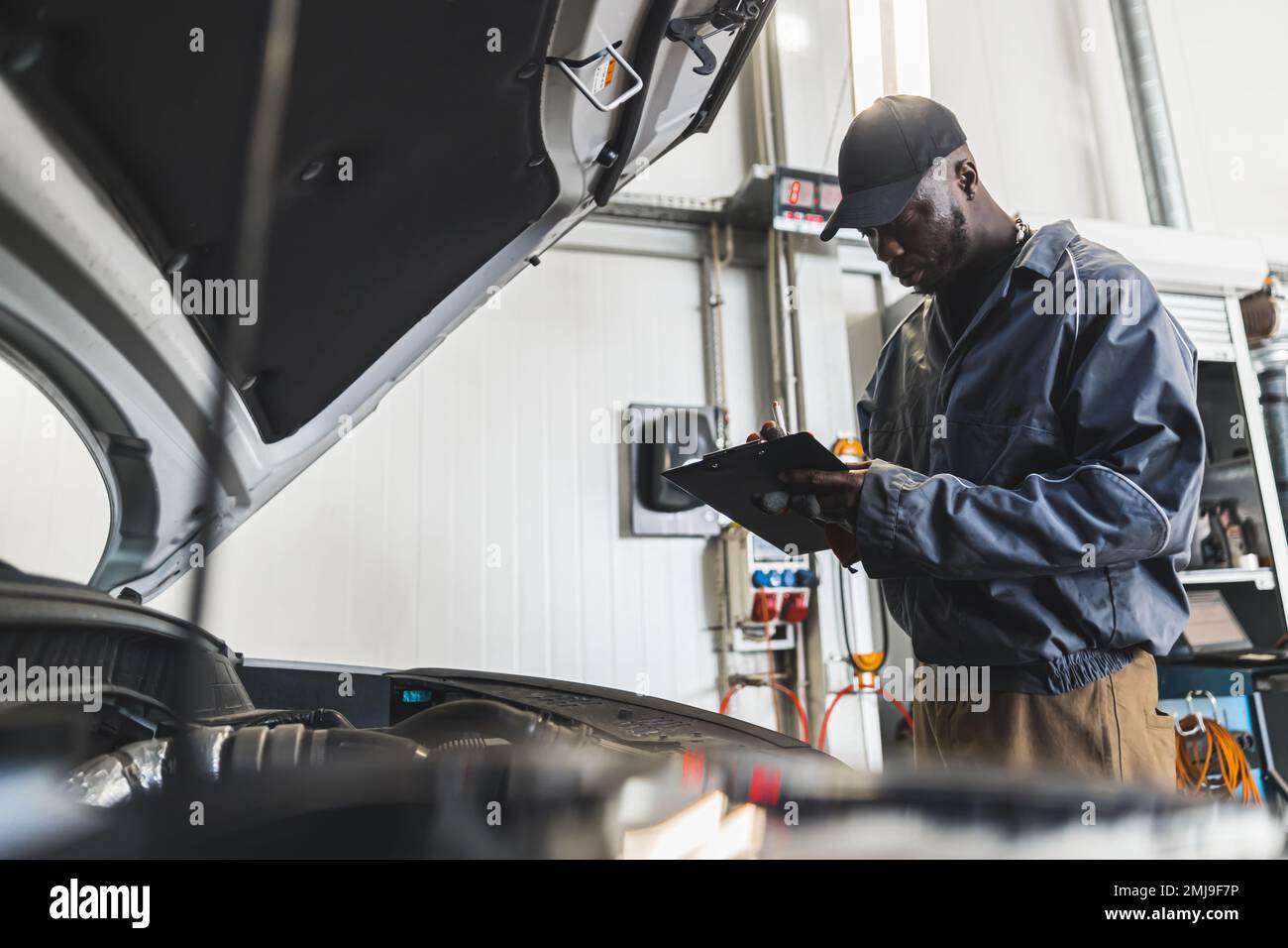 Skilled car mechanic inspects the car engine at the repair facility and ...