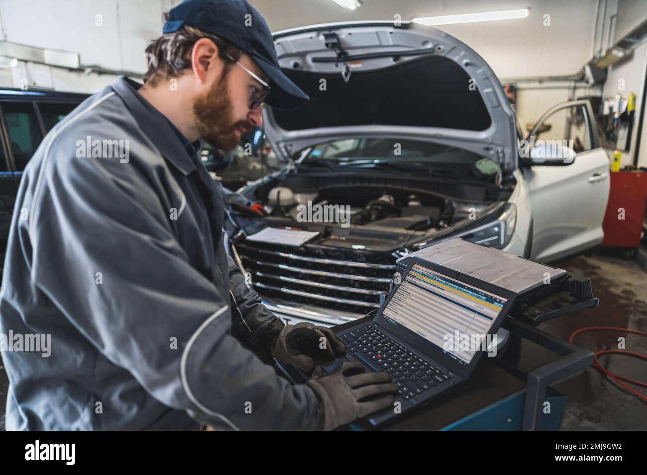 Medium shot of a mechanic doing car computer diagnostics. Repair shop ...