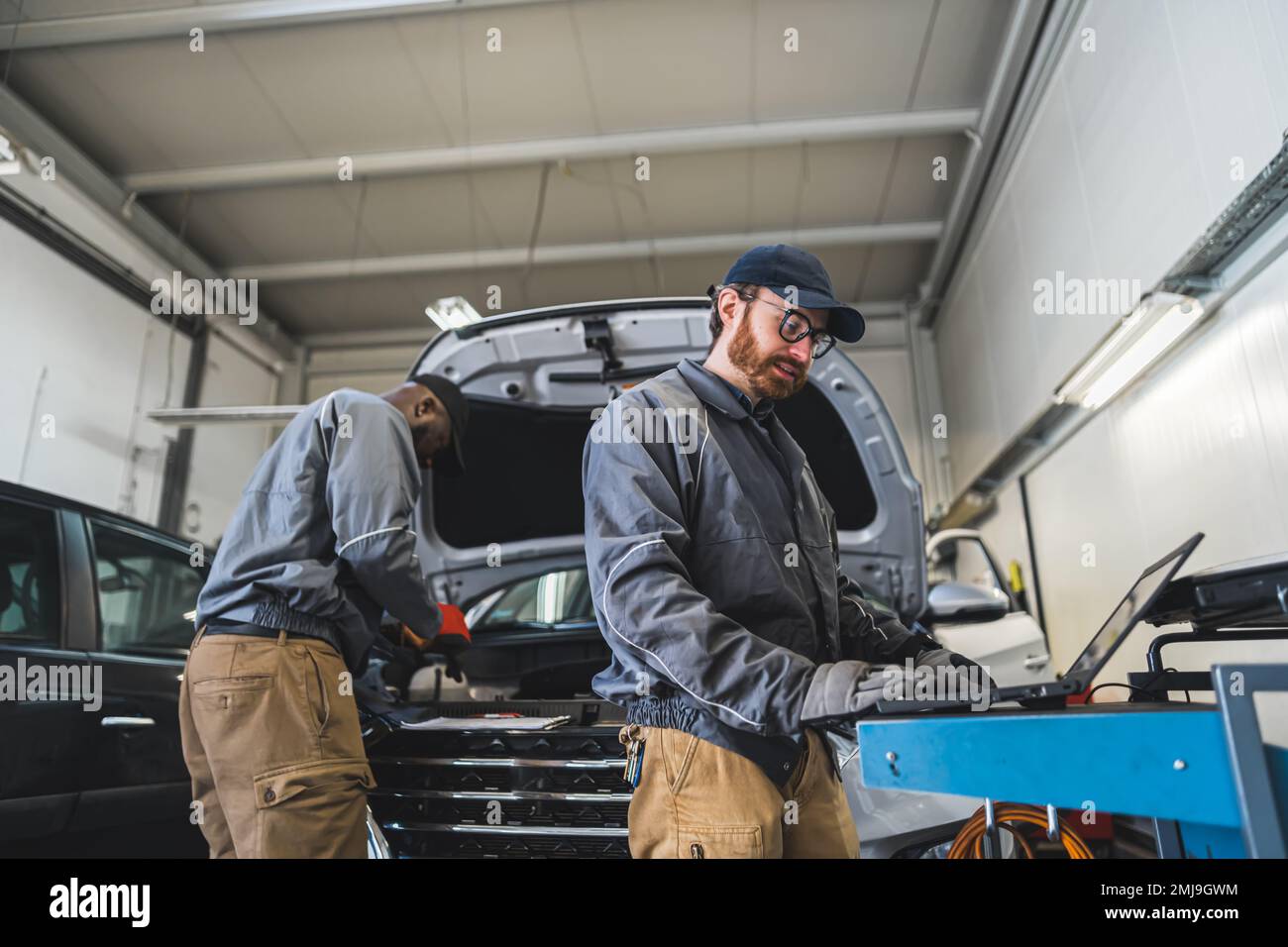 Skilled car mechanic repairing a car using computer diagnostic modern ...