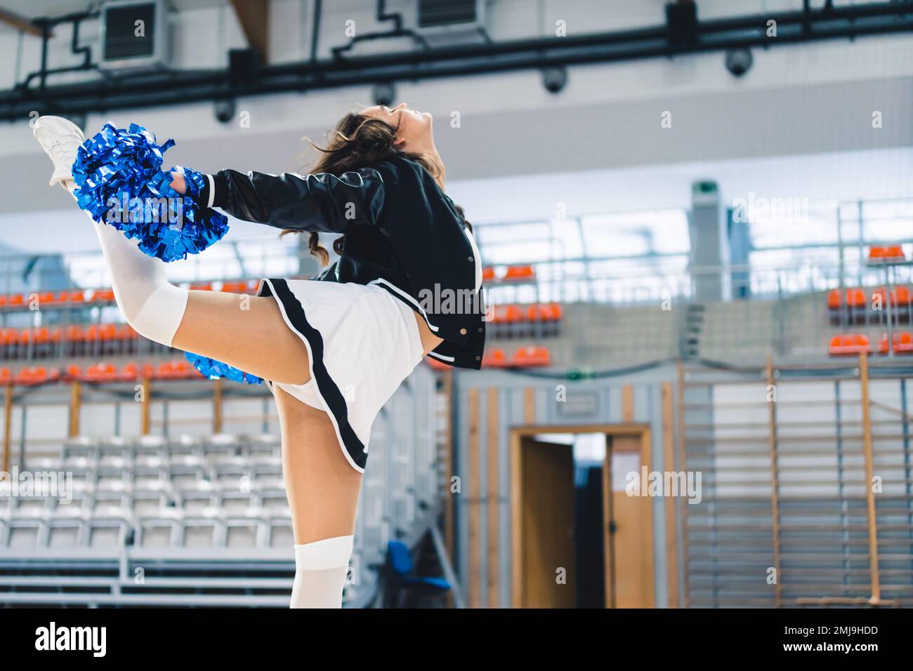 Cheerleader In Black And White Uniform Standing On One Leg While