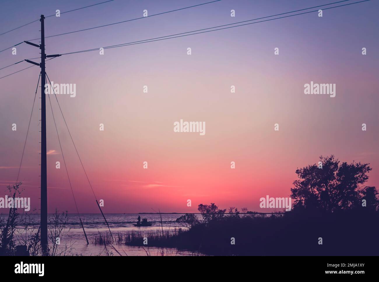 A man fishes as the sun sets over Heron Bay, Jan. 19, 2023, in Coden ...