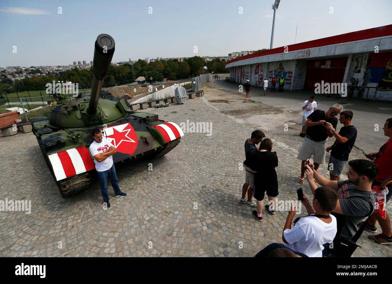 People pose with a former Yugoslav army T-55 battle tank seen in front ...