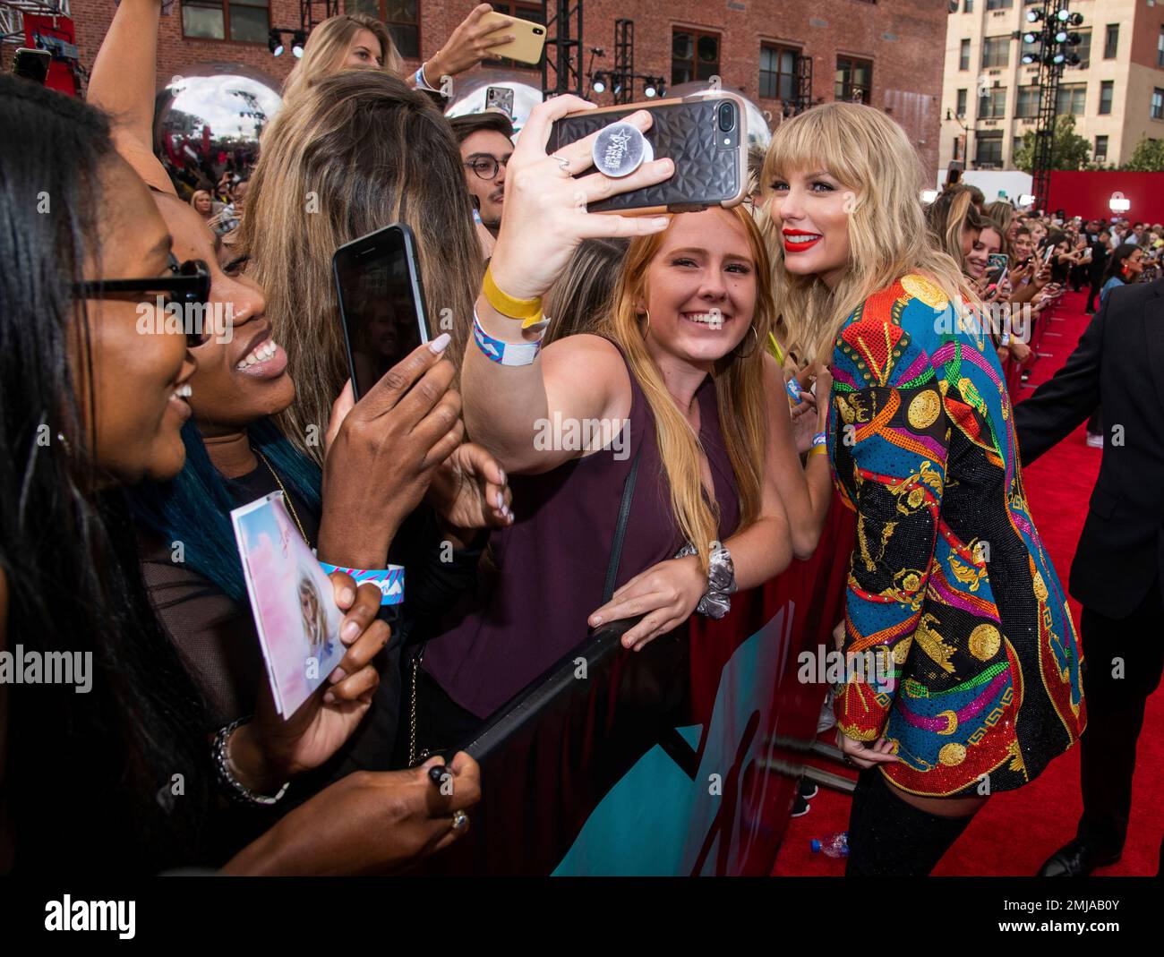 Taylor Swift, right, takes selfies with fans as she arrives at the MTV ...