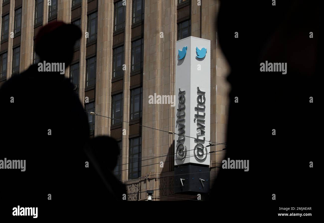 Pedestrians walk across the street from the Twitter office building in ...