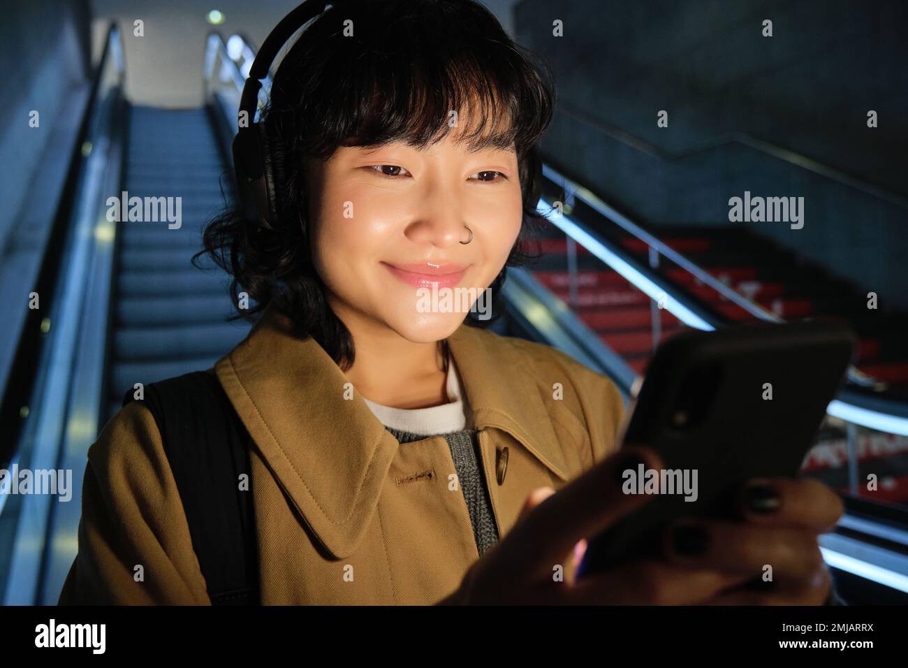 Close up of cute asian girl in headphones, picks song to listen while ...