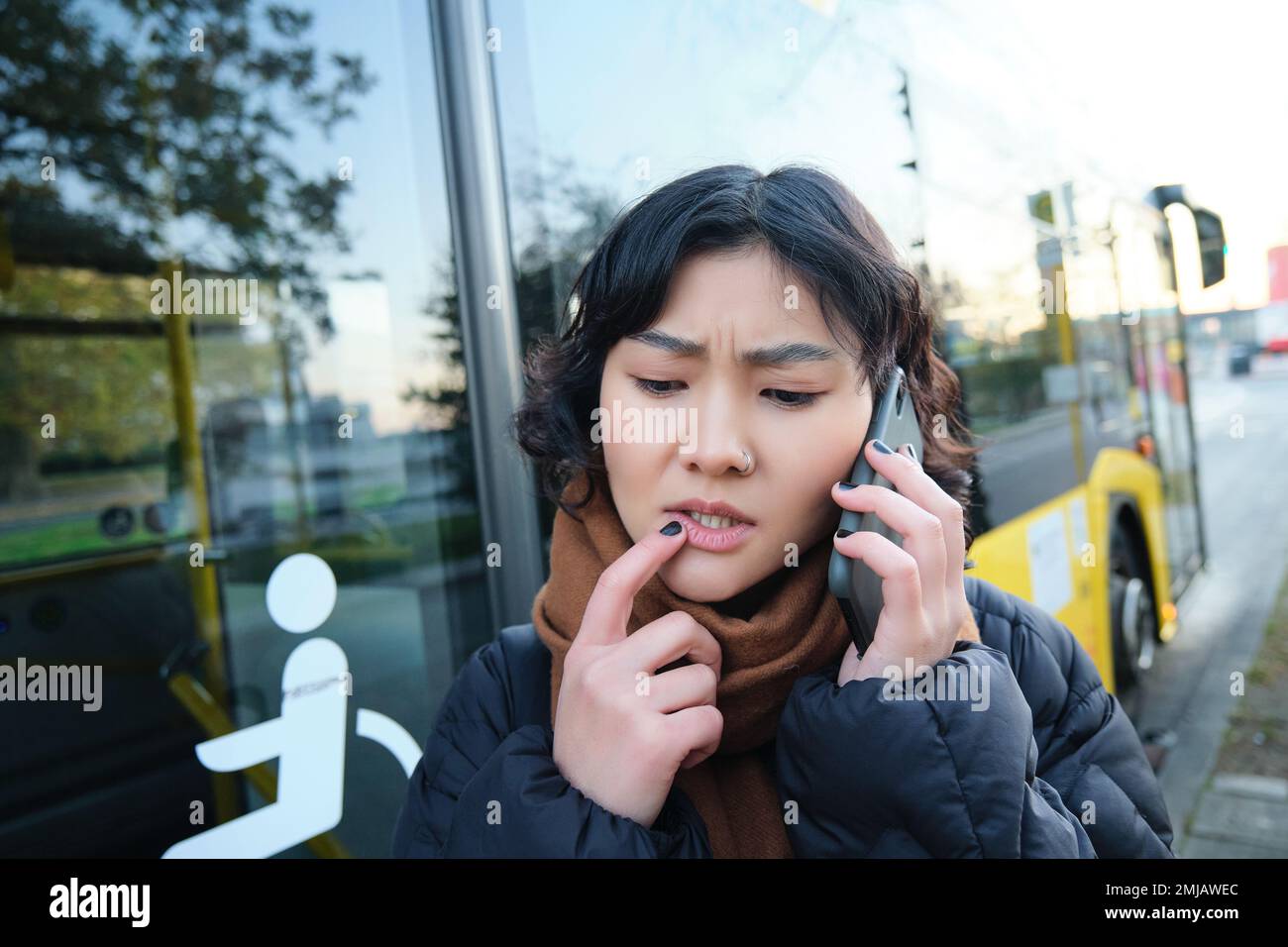 Perplexed asian girl, talks on mobile phone with concerned, thoughtful ...