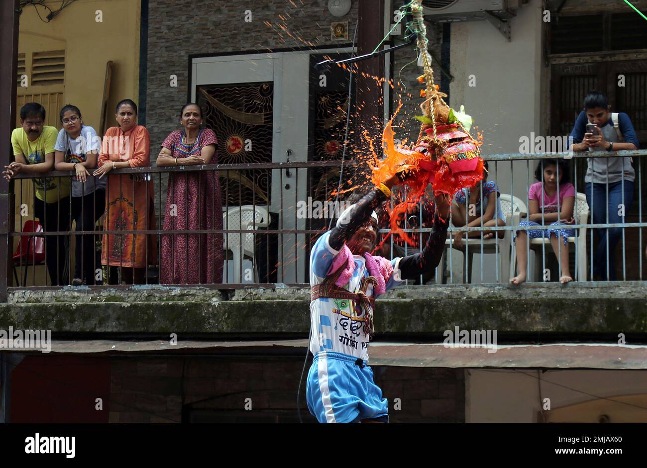 Residents watch an Indian Hindu devotee breaking a pot containing curd ...