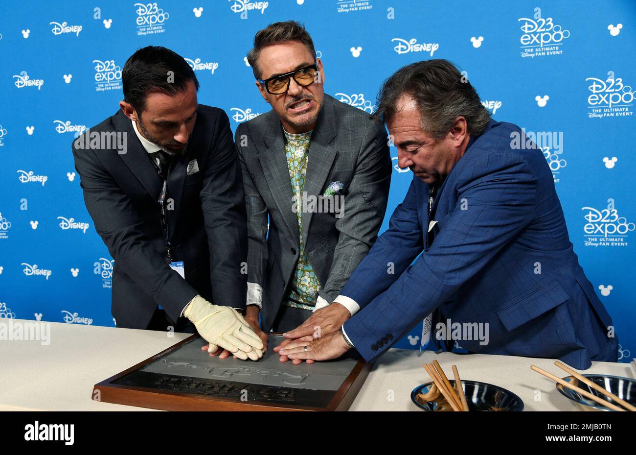 Attendants help actor Robert Downey Jr., center, press his hands in ...