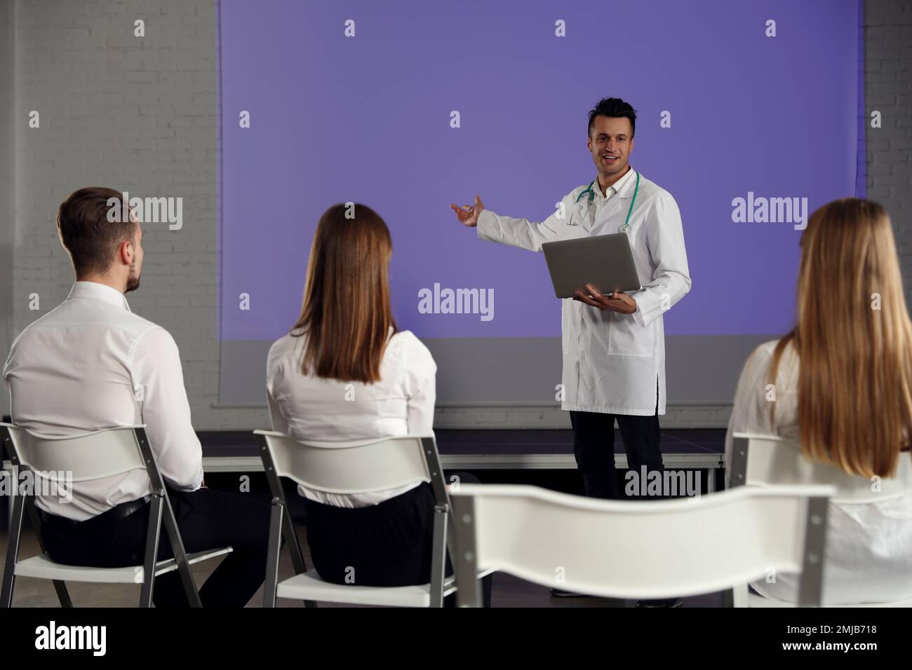 Male doctor with laptop giving lecture in conference room with ...