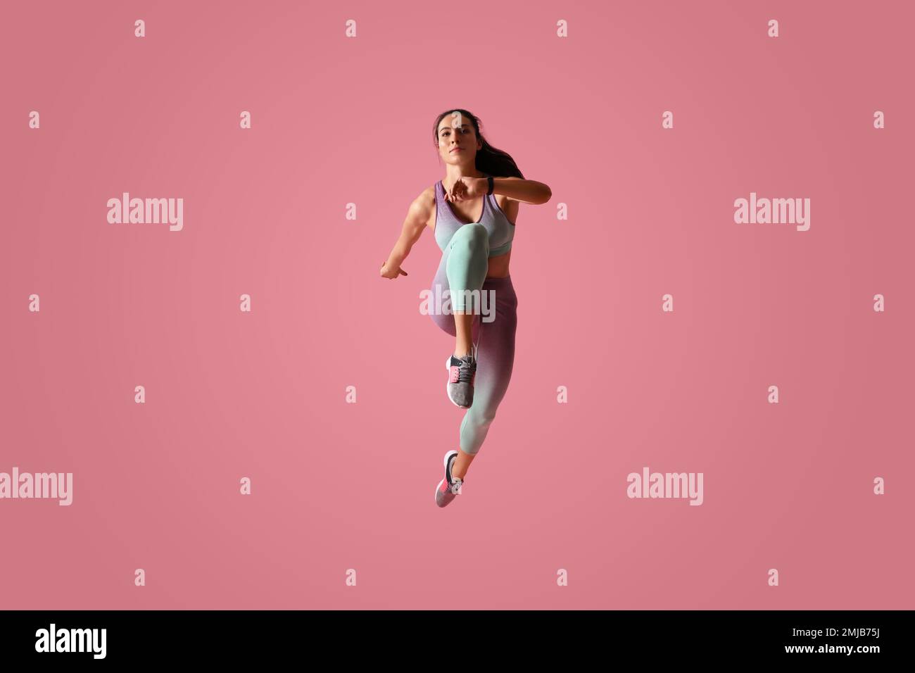 Athletic young woman running on pink background Stock Photo - Alamy