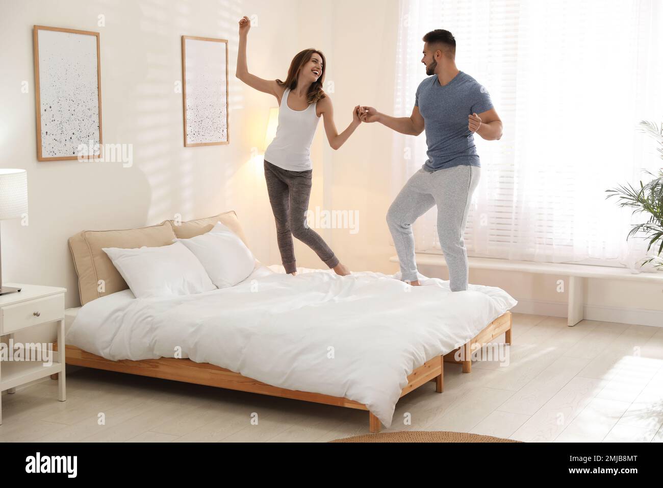 Lovely young couple dancing on bed at home Stock Photo - Alamy