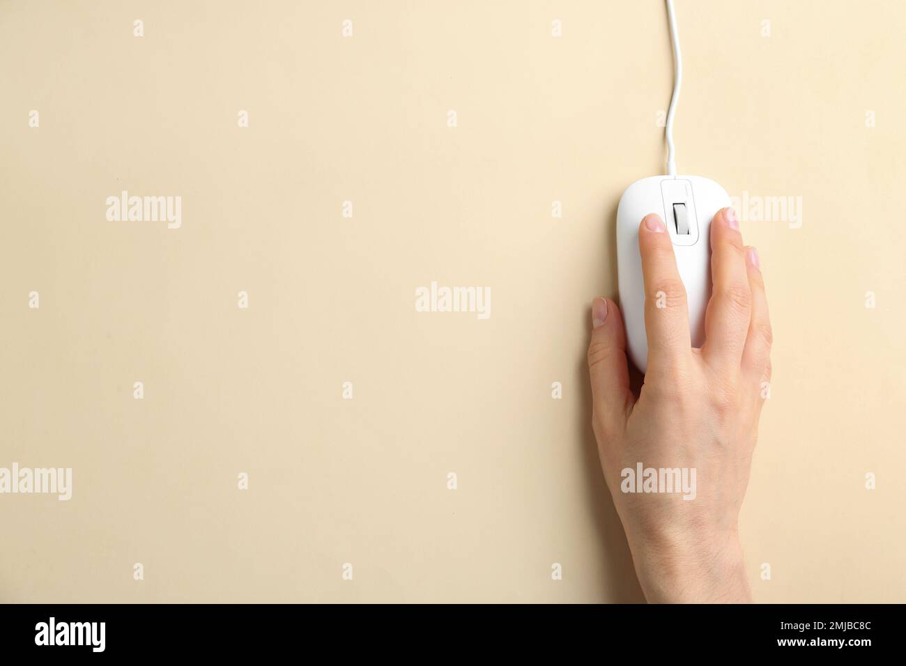 Woman using modern wired optical mouse on beige background, top view ...