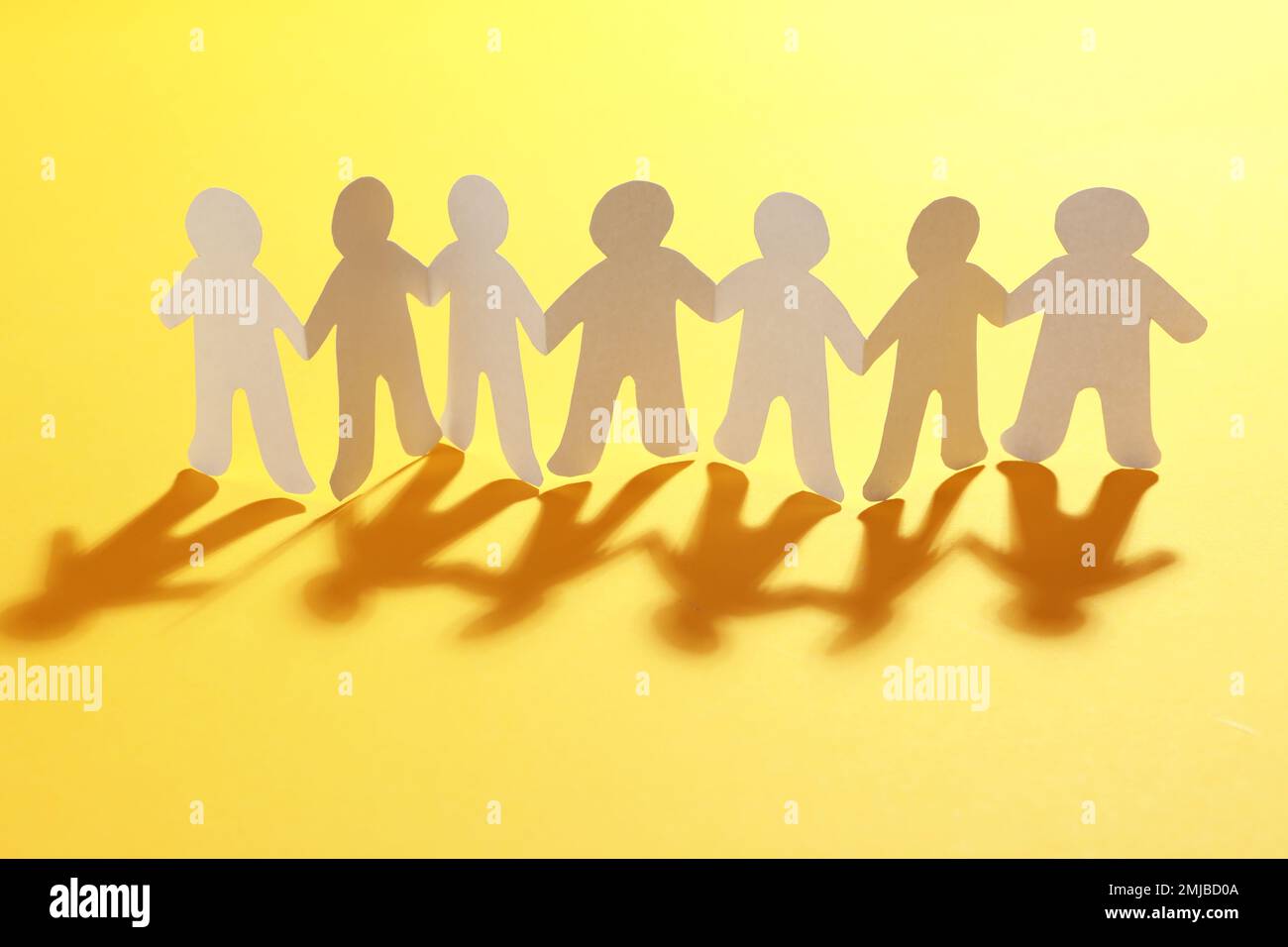 Paper people chain on yellow background. Unity concept Stock Photo - Alamy