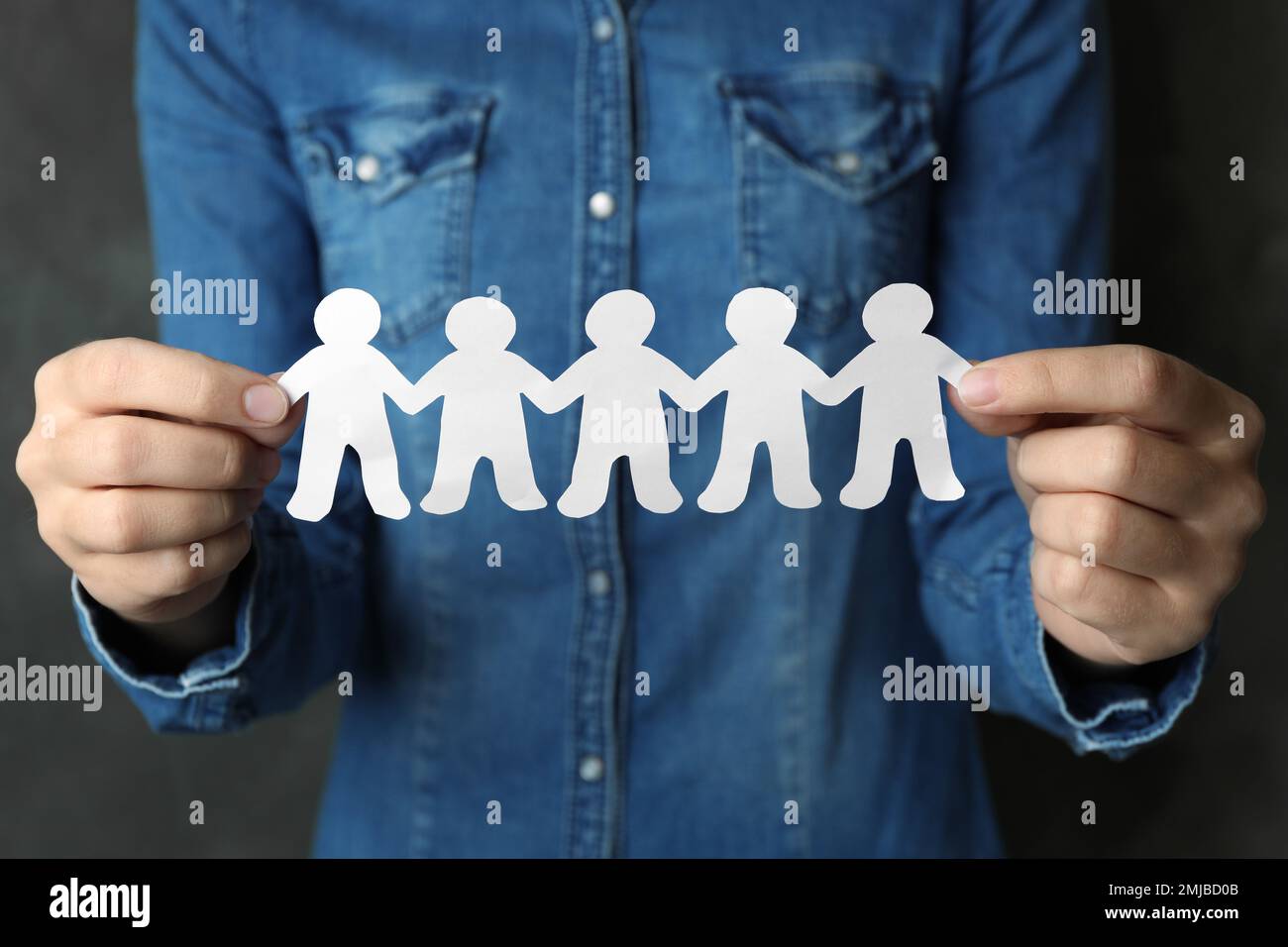 Woman holding paper people chain on grey background, closeup. Unity ...