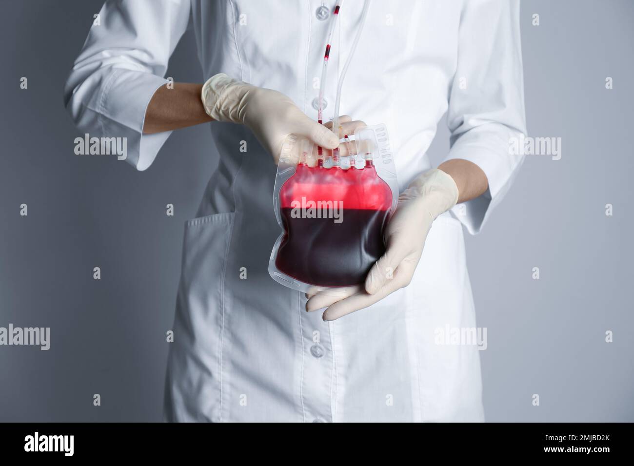 Woman holding blood for transfusion on light grey background, closeup ...