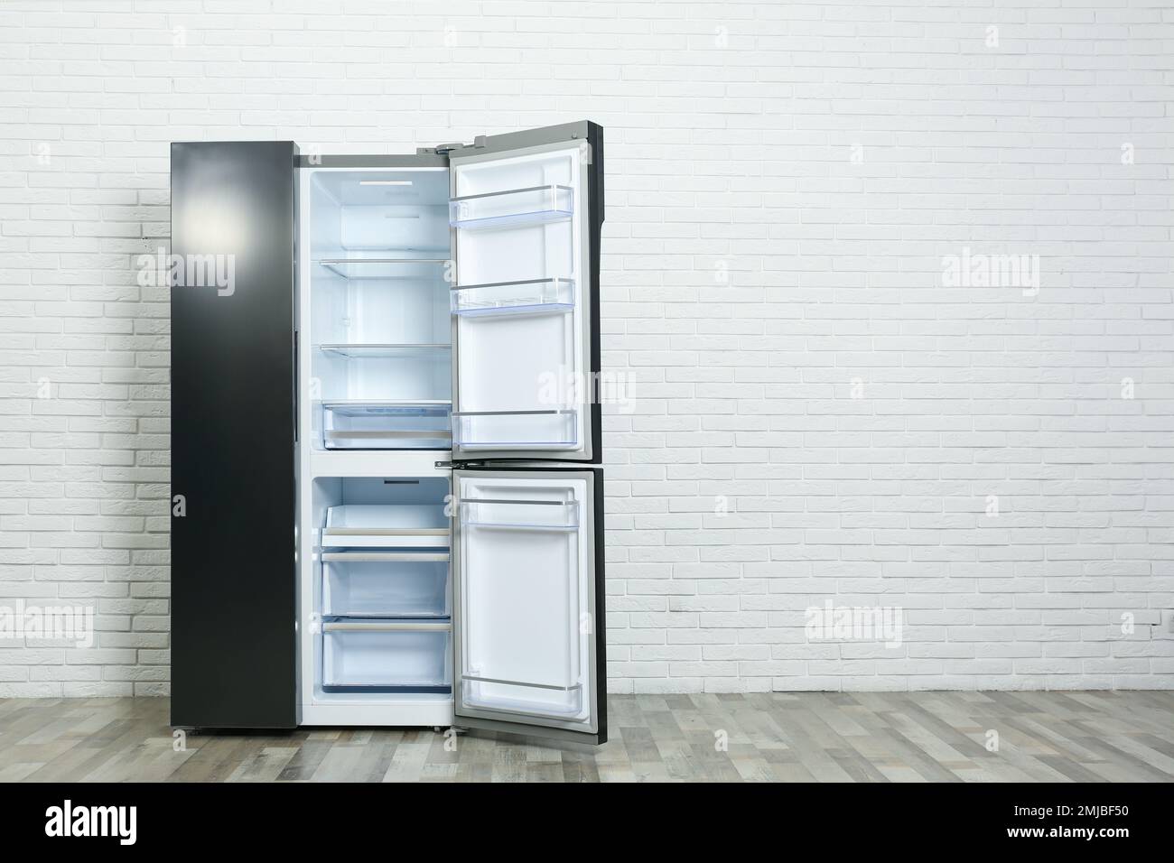 Modern empty refrigerator near white brick wall, space for text Stock ...