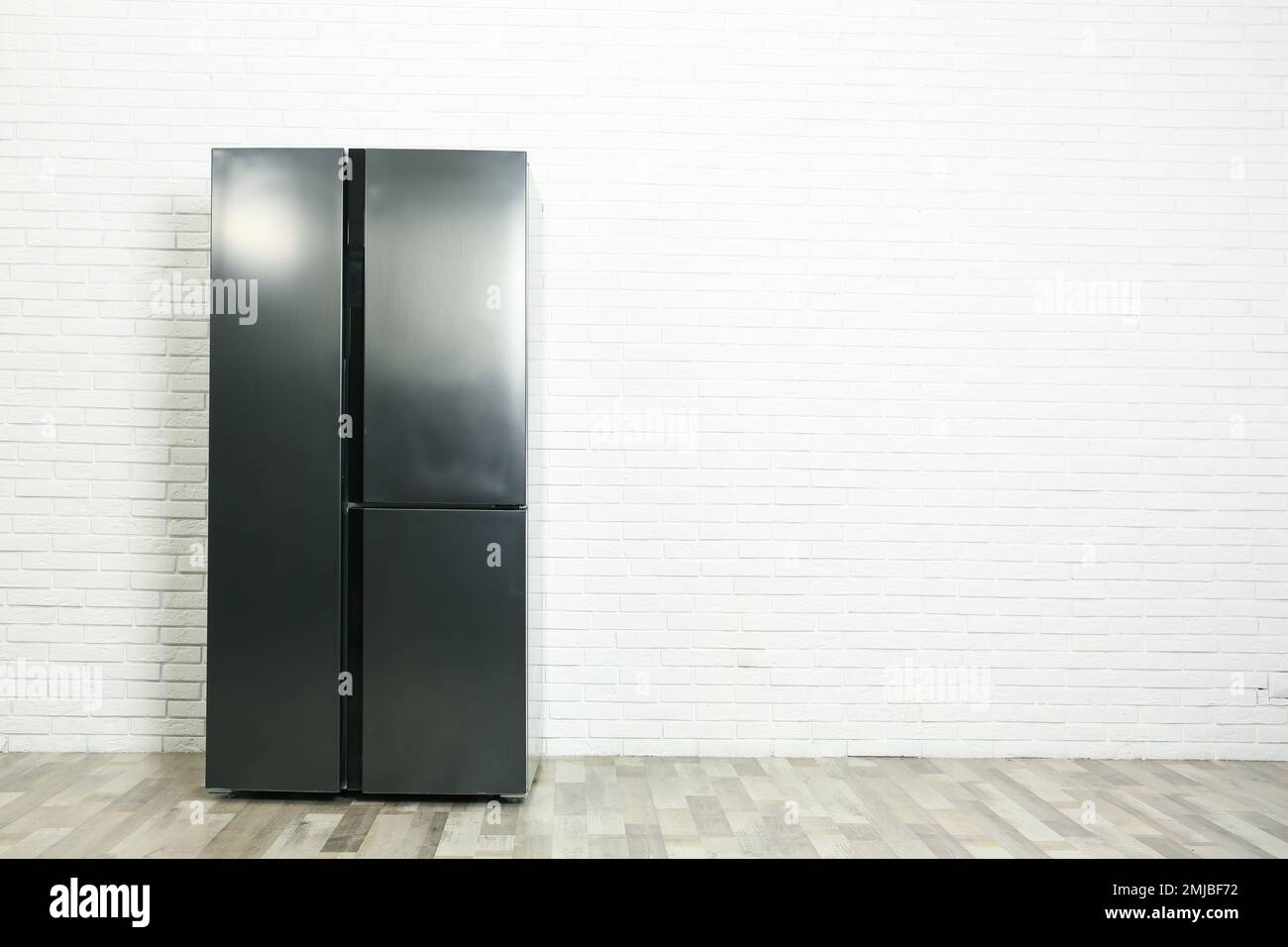 Modern refrigerator near white brick wall, space for text Stock Photo ...