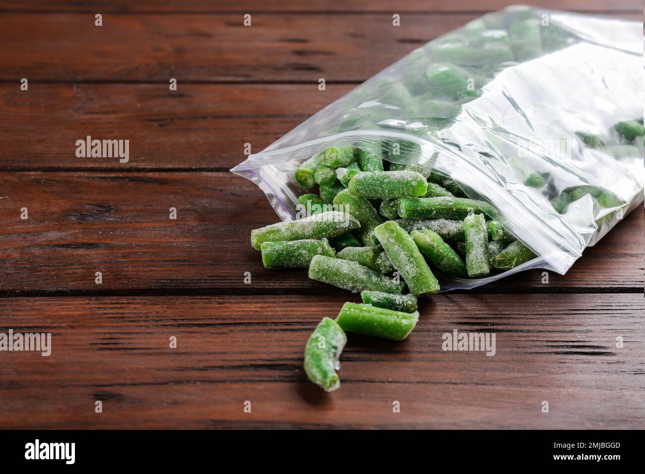 Frozen cut green beans on wooden table. Vegetable preservation Stock ...
