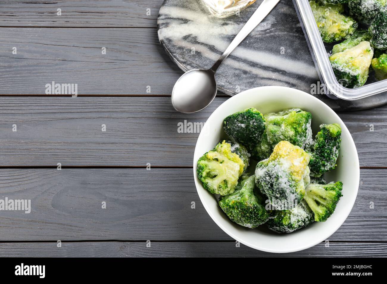 Flat lay composition with frozen broccoli on light grey wooden table ...