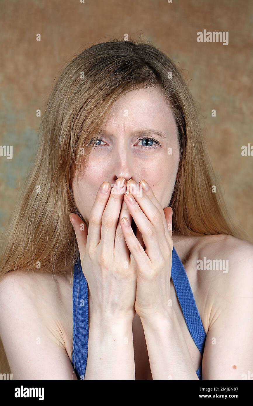 Young woman holding hand across mouth to hide disgust expression on her ...