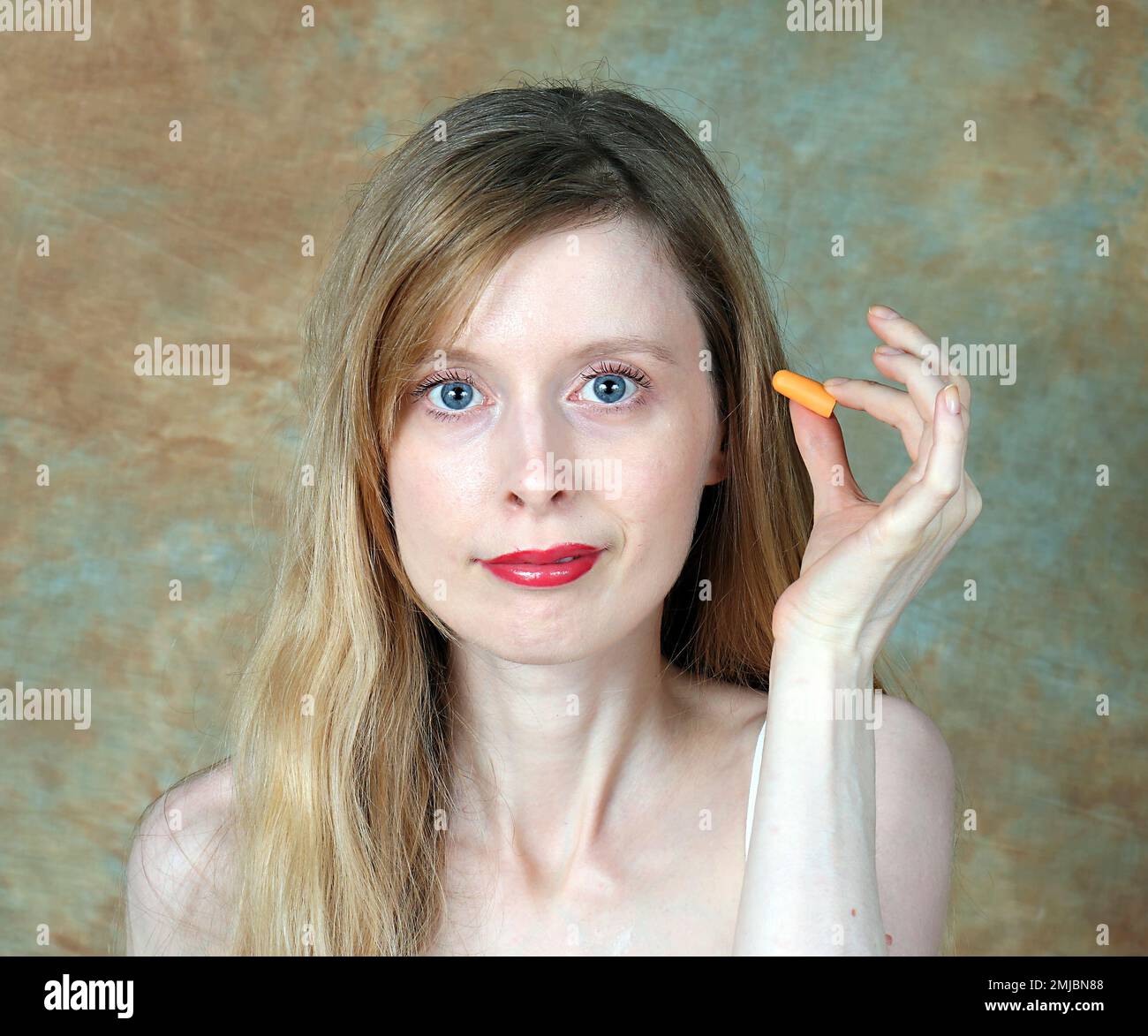 Young woman holding foam ear plug ready to use it against noise ...