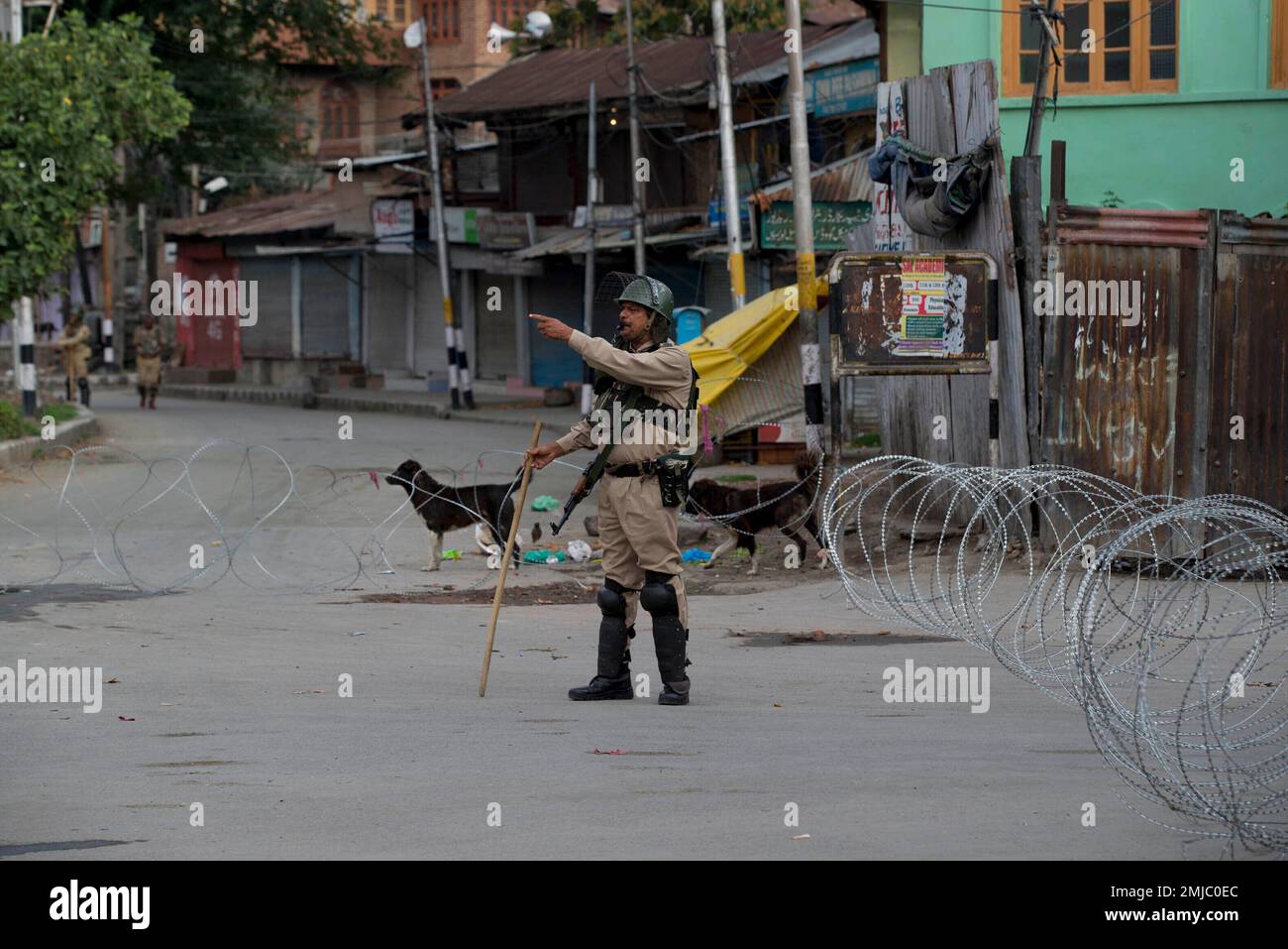 An Indian paramilitary soldier gestures towards a Kashmiri man as he ...