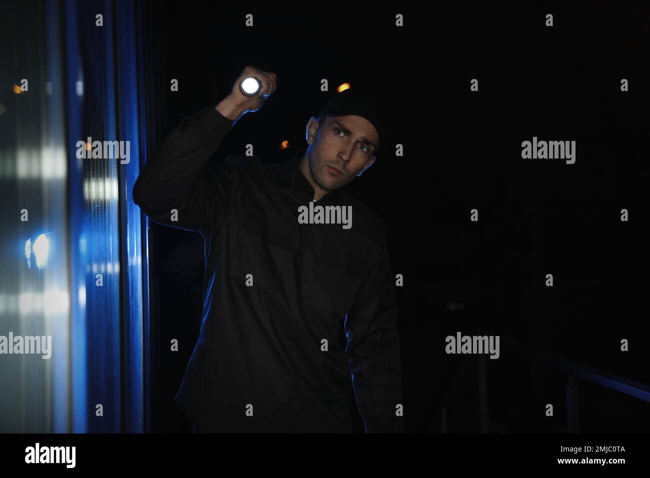 Male security guard with flashlight in dark corridor Stock Photo - Alamy