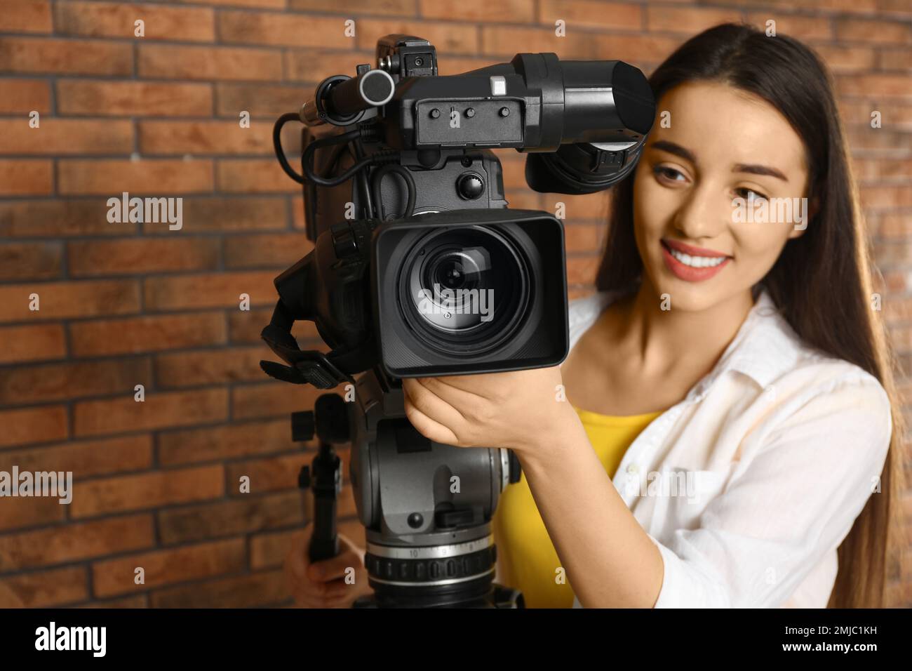 Operator with professional video camera near brick wall Stock Photo - Alamy