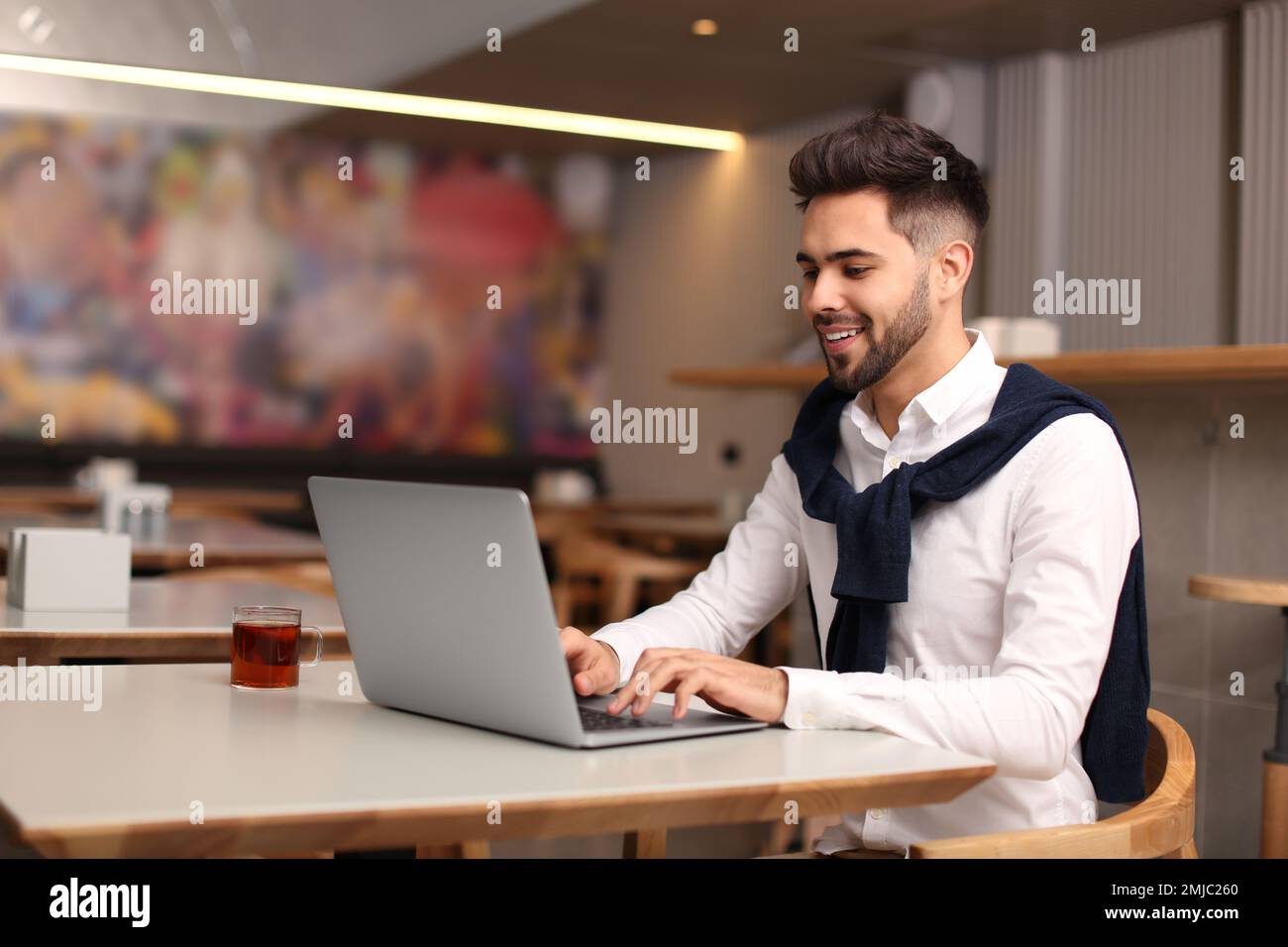 Young male business owner working with laptop in his cafe Stock Photo ...
