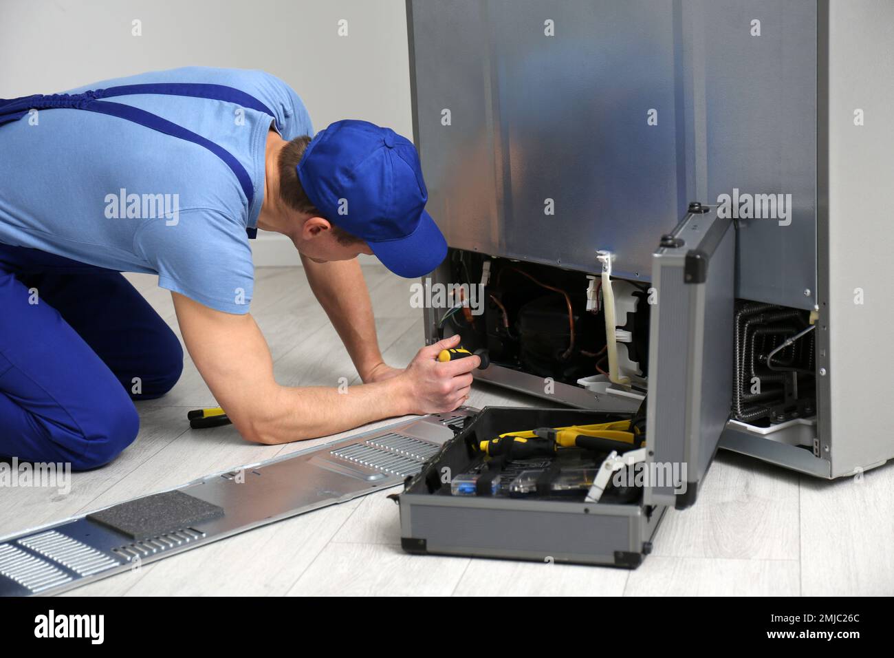 Male technician with screwdriver repairing refrigerator indoors Stock ...