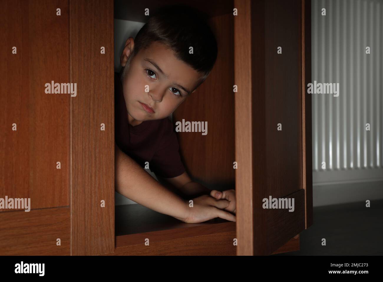 Sad little boy hiding in wardrobe. Domestic violence concept Stock ...